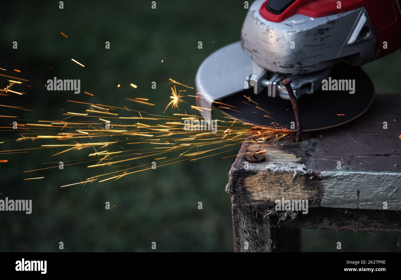 Rotary flex cutter cutting rusty nail on old wooden frame, sparks ...
