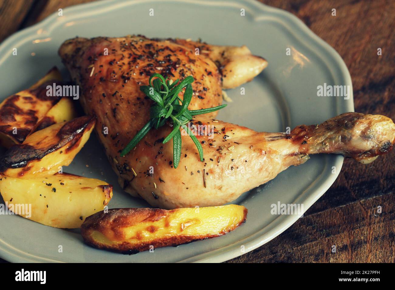 Grilled chicken quarter with potato for garnish. Top view. Wooden ...