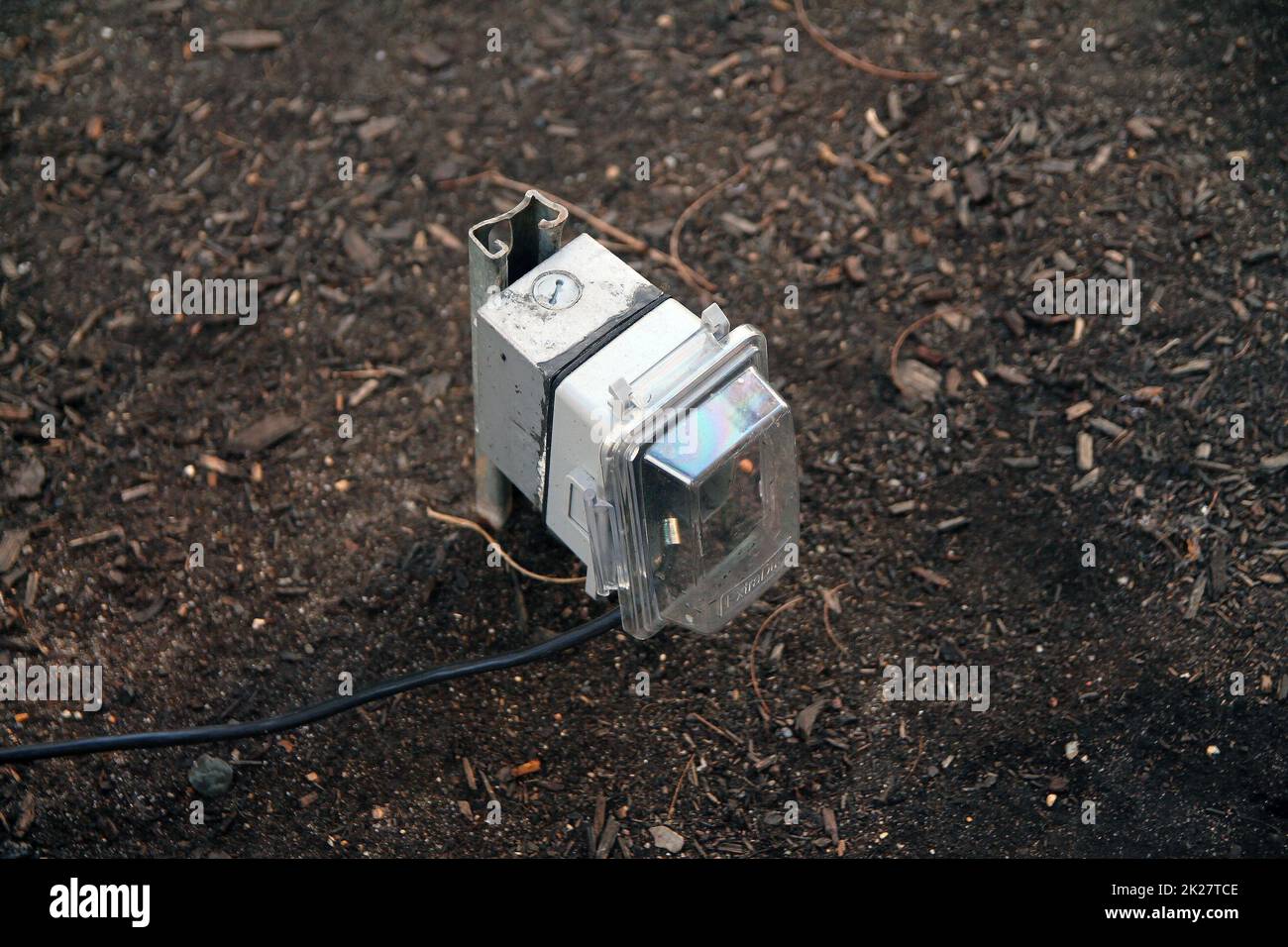 Outdoors public electric outlet with rain cover and a black plugged ...