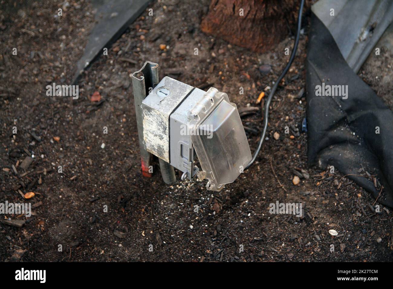 Outdoors public electric outlet with rain cover and a black plugged ...