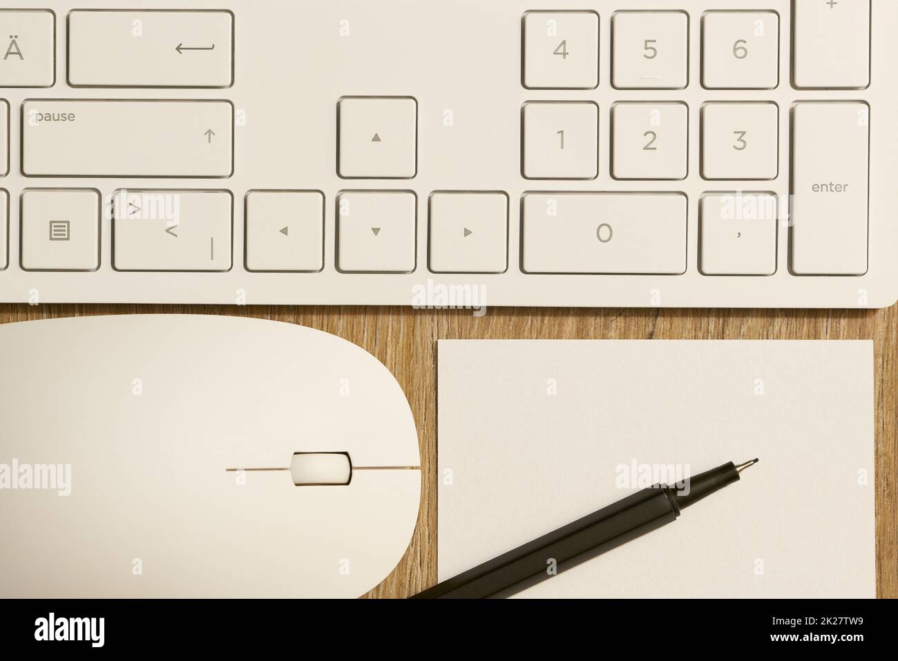 Keyboard from a computer and a computer mouse and pen and paper on a ...