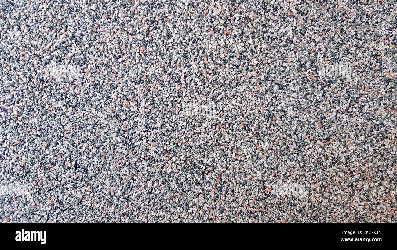 Gray concrete surface with multi-colored marble chips. Foreground. Dark ...