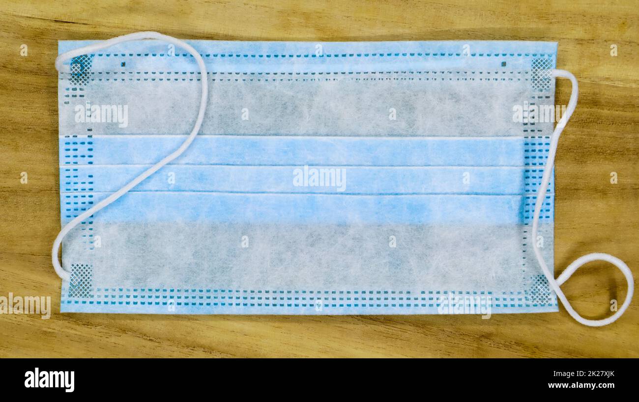 One 3-ply disposable surgical face mask with rubber pads covering the ...