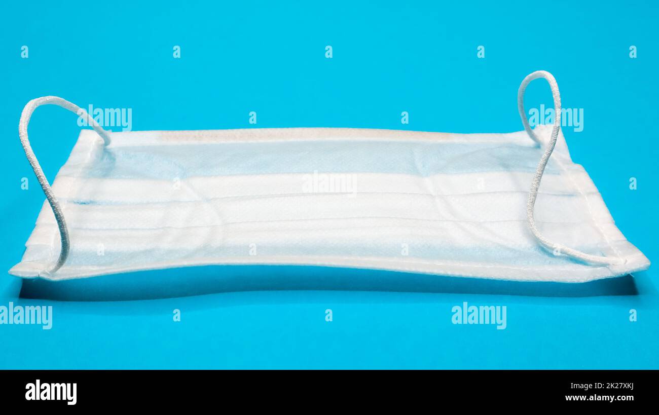 One 3-ply disposable surgical face mask with rubber grips covering ...