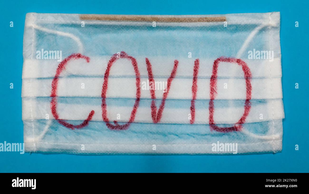 Typical white 3-ply surgical mask with rubber earhooks to cover mouth ...