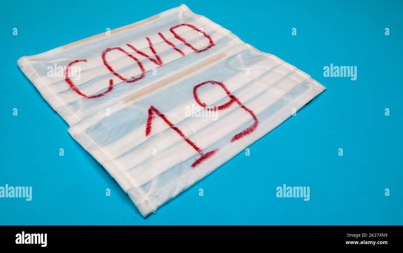 Typical white 3-ply surgical mask with rubber earhooks to cover mouth ...