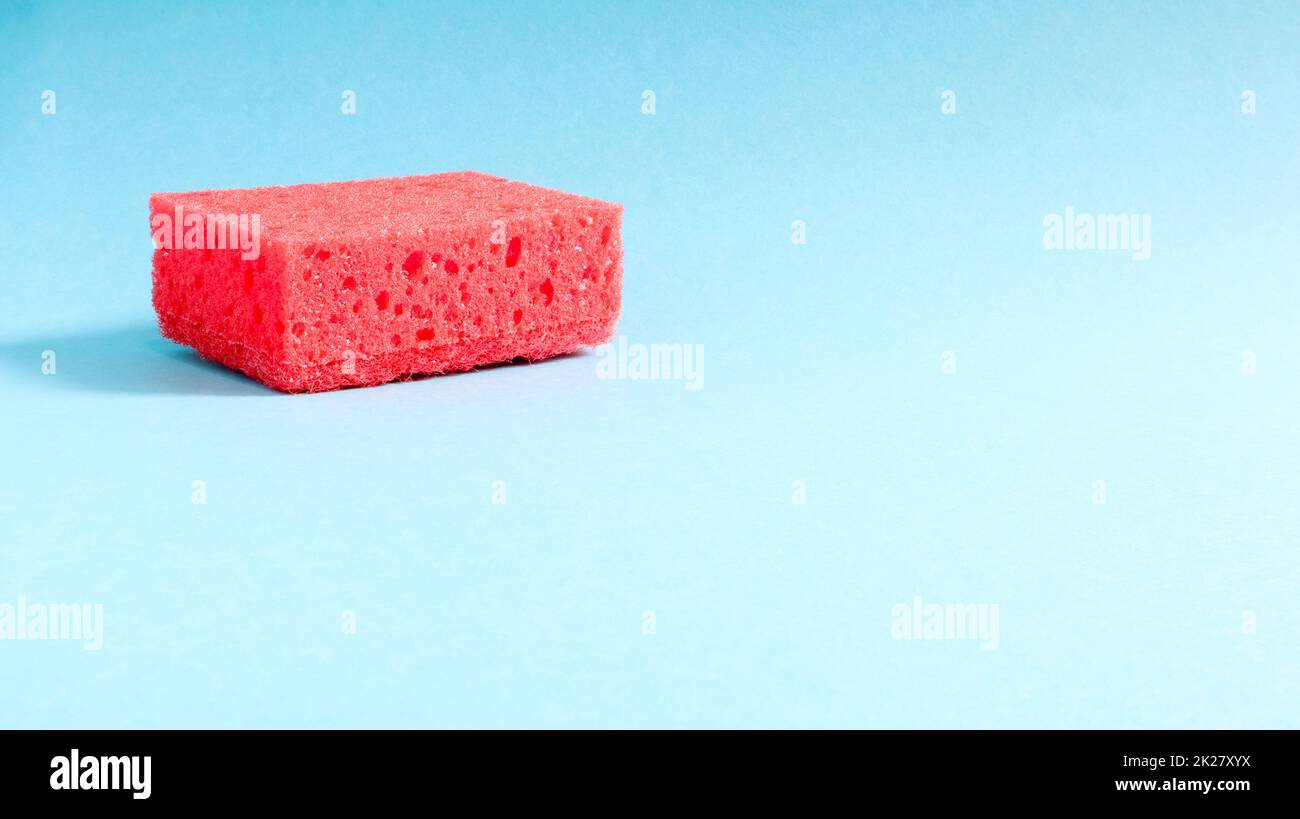 One red sponge on a blue background is used to wash and erase the dirt ...