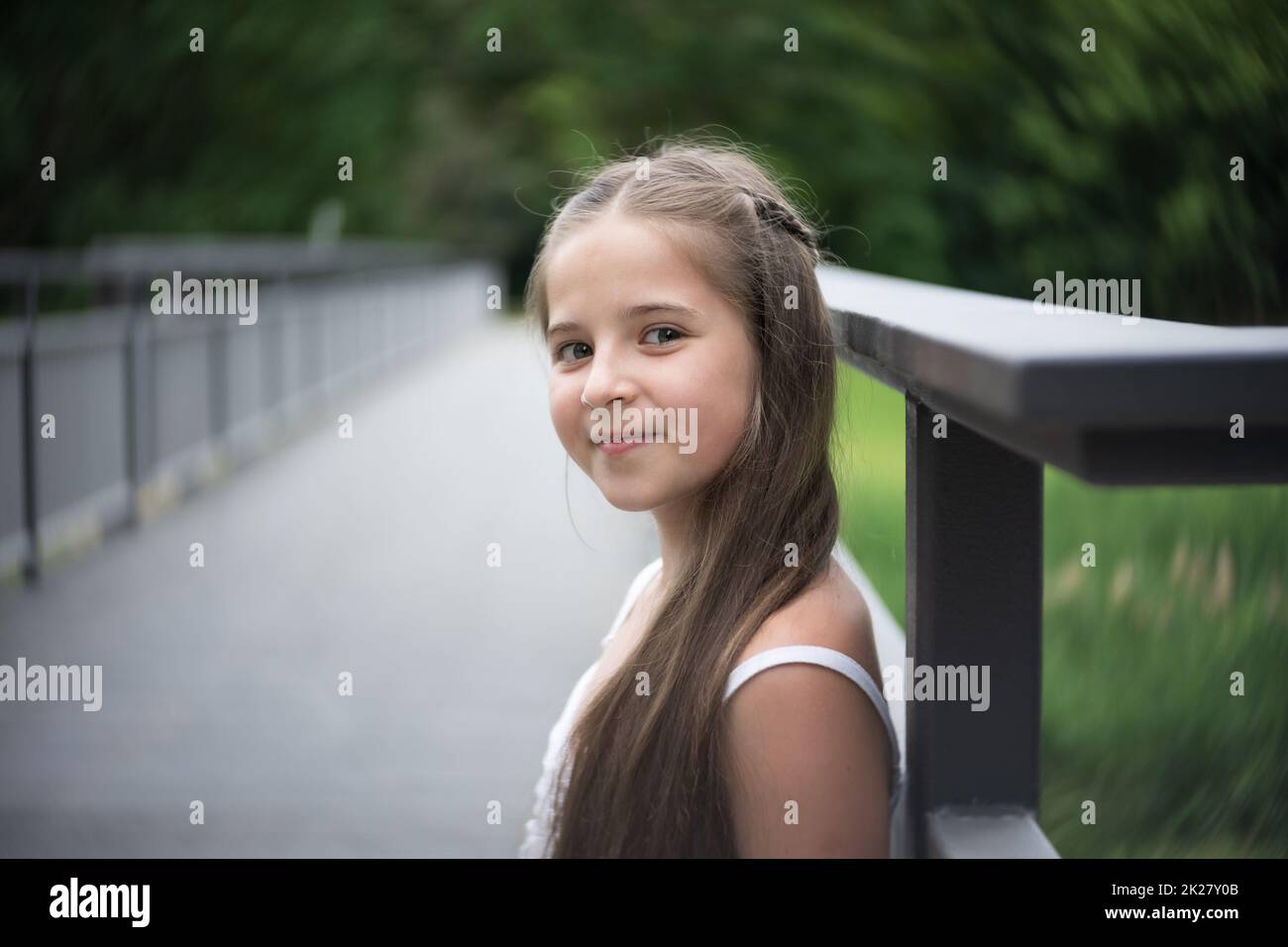 Portrait of a beautiful girl with long hair standing on a bridge Stock ...