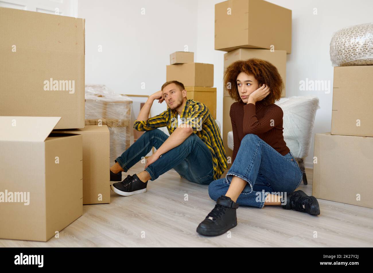 Tired multiracial couple sitting among cardboard boxes Stock Photo - Alamy