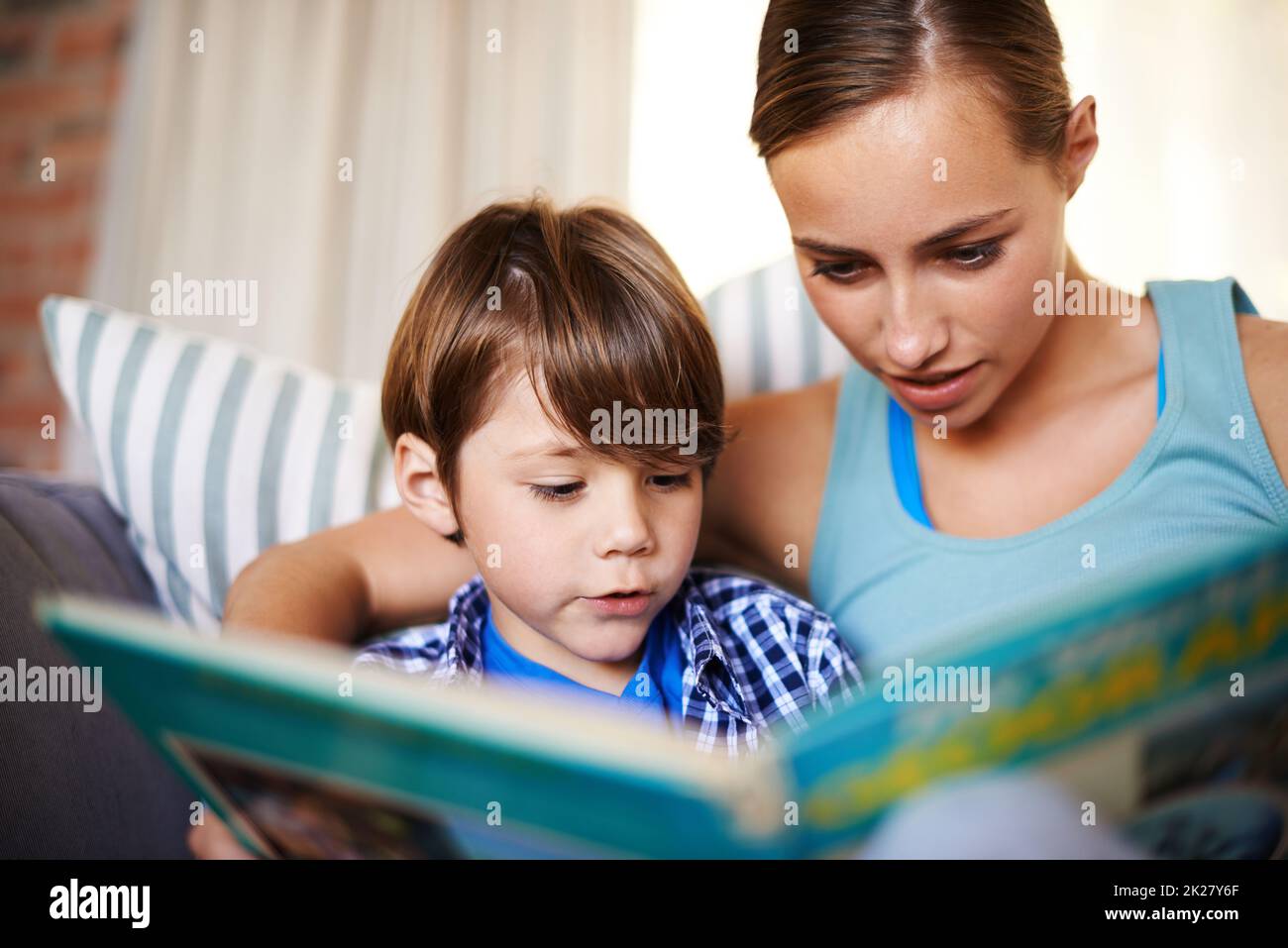 Helping her son with his reading. a young mother and her son reading ...