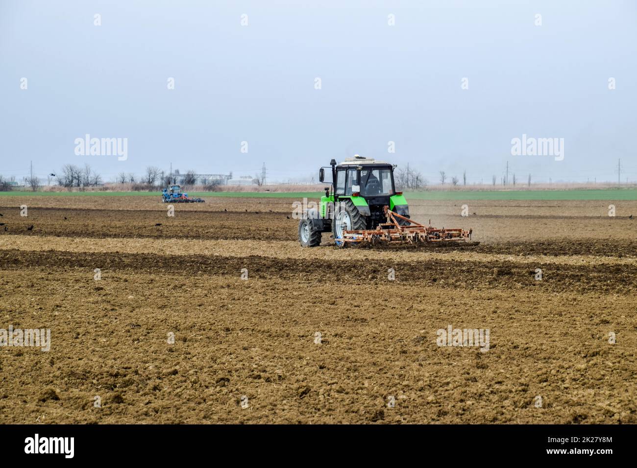 Lush and loosen the soil on the field before sowing. The tractor plows ...