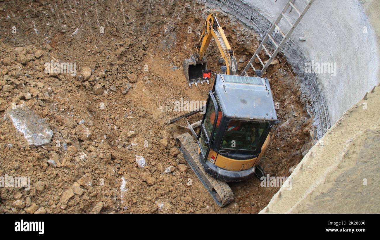 Small excavator is digging in a pit Stock Photo - Alamy