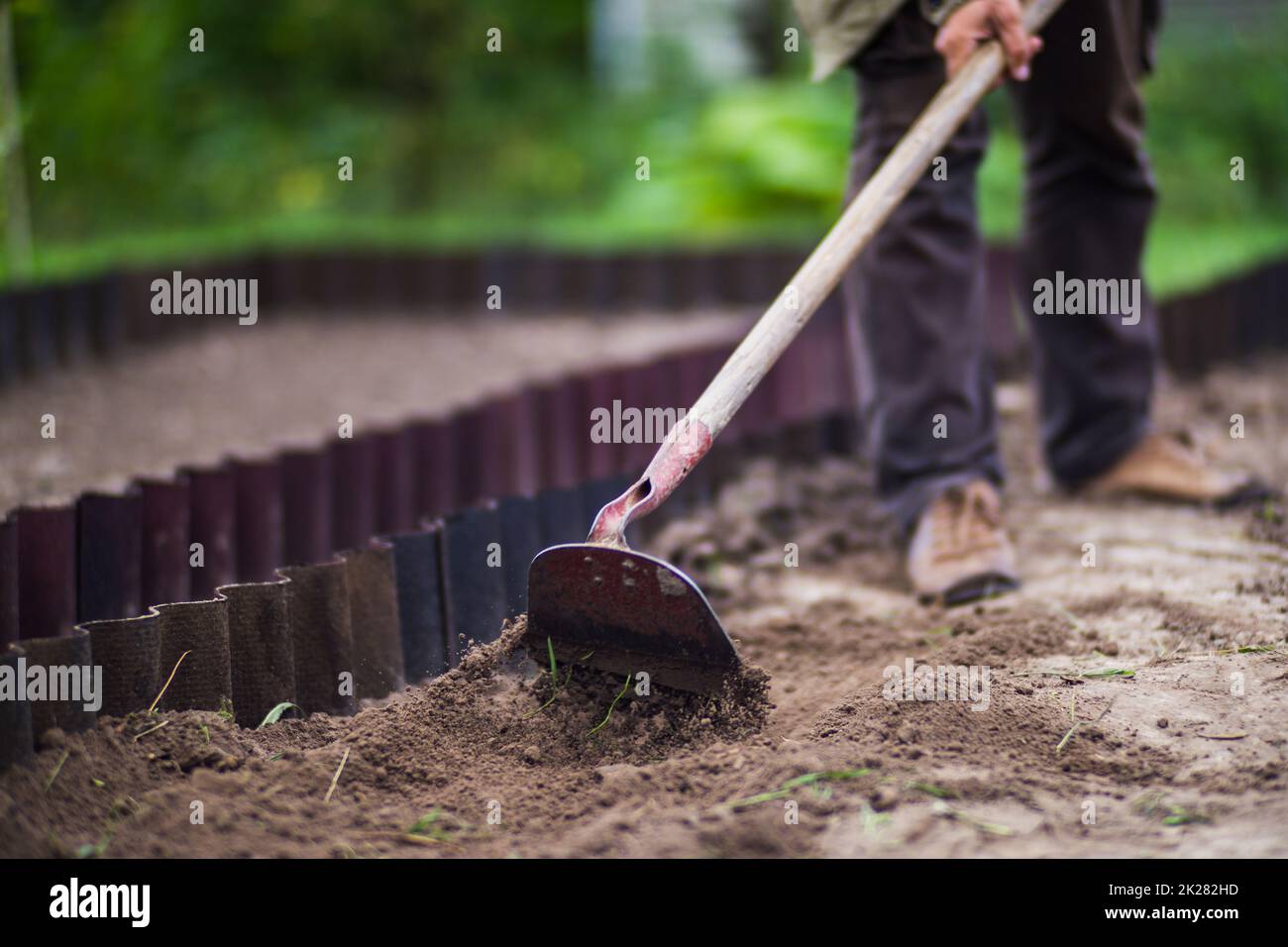 Farmer cultivating land in the garden with hand tools. Soil loosening ...