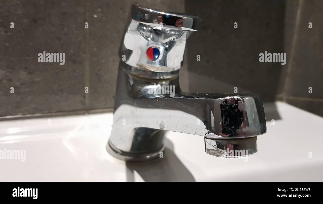 white ceramic washbasin with chrome faucet in the toilet with gray tile ...