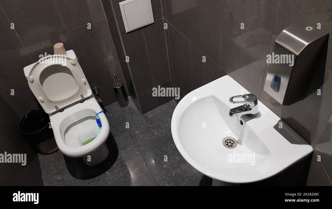 white ceramic washbasin with chrome faucet in the toilet with gray tile ...