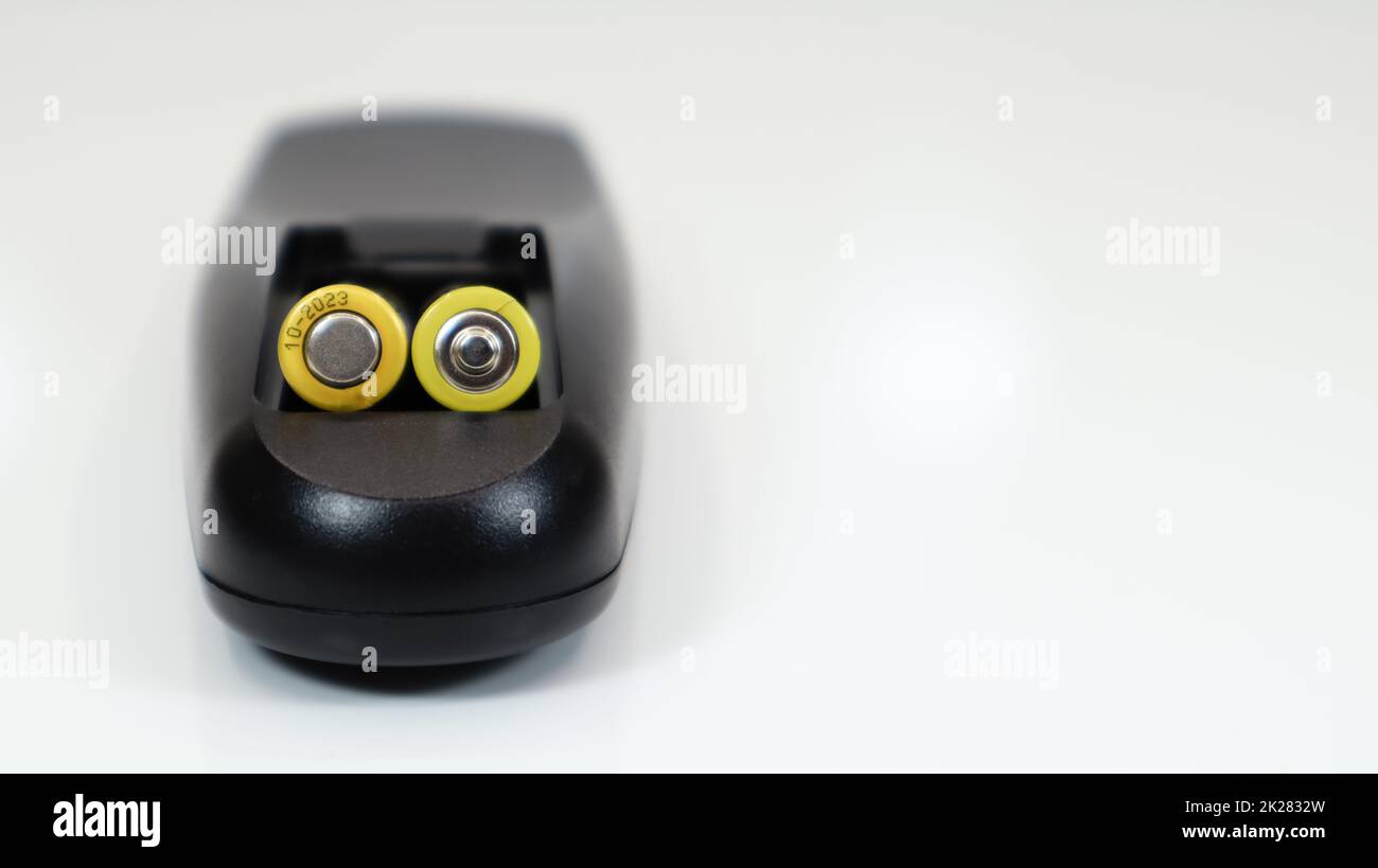 Black remote control with yellow AAA batteries on a white background ...