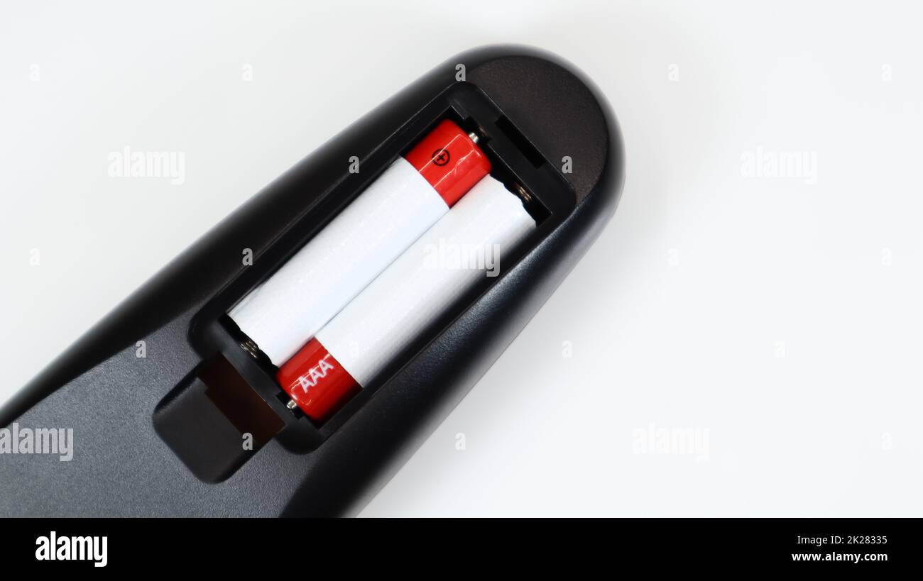 Black TV remote control with AAA alkaline batteries in red and white on ...