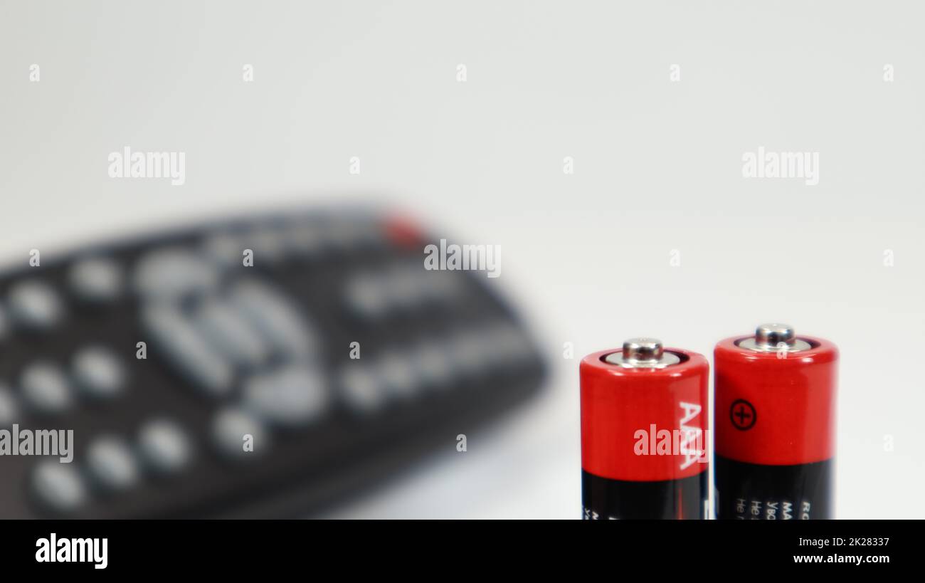 Black TV remote control with AAA alkaline batteries in red and white on ...