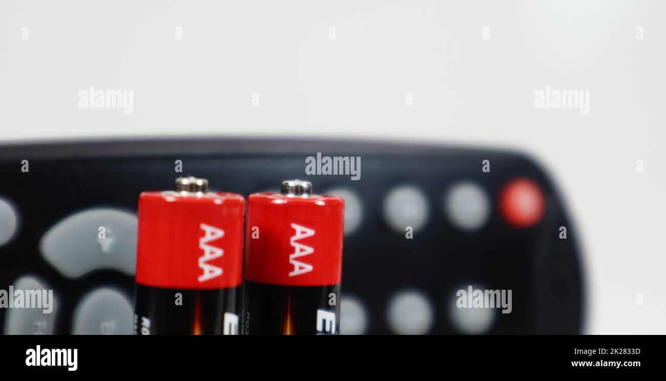Black TV remote control with AAA alkaline batteries in red and white on ...