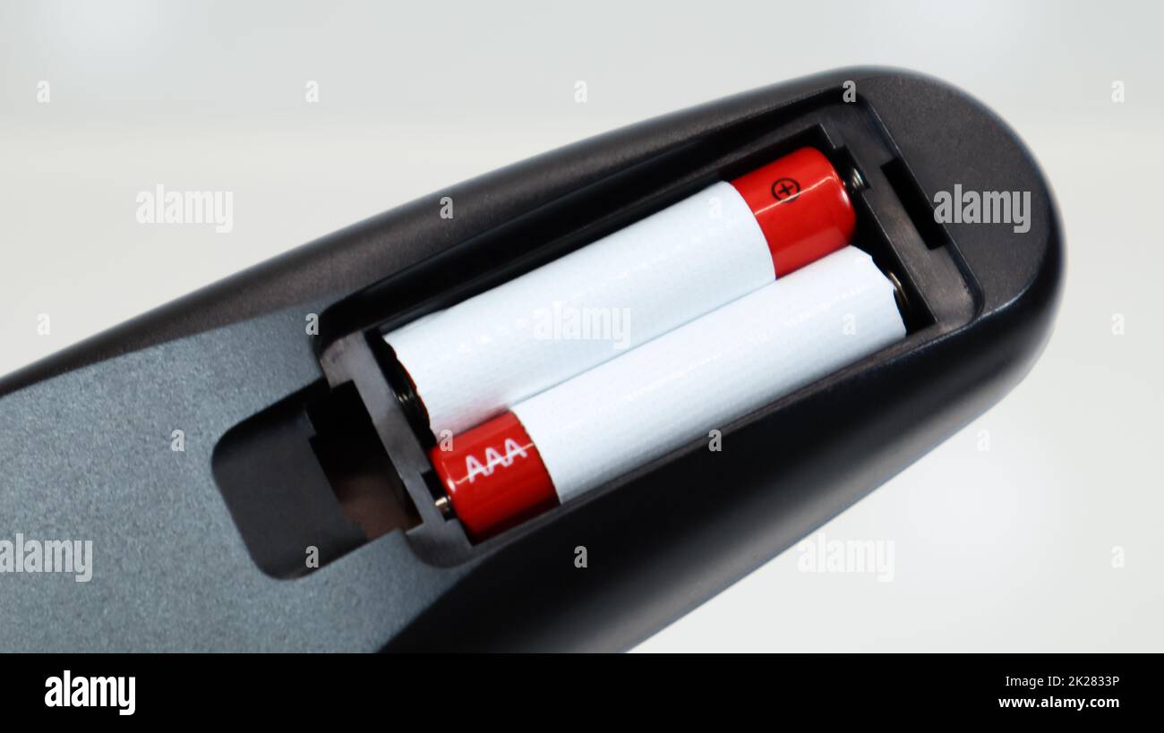 Black TV remote control with AAA alkaline batteries in red and white on ...