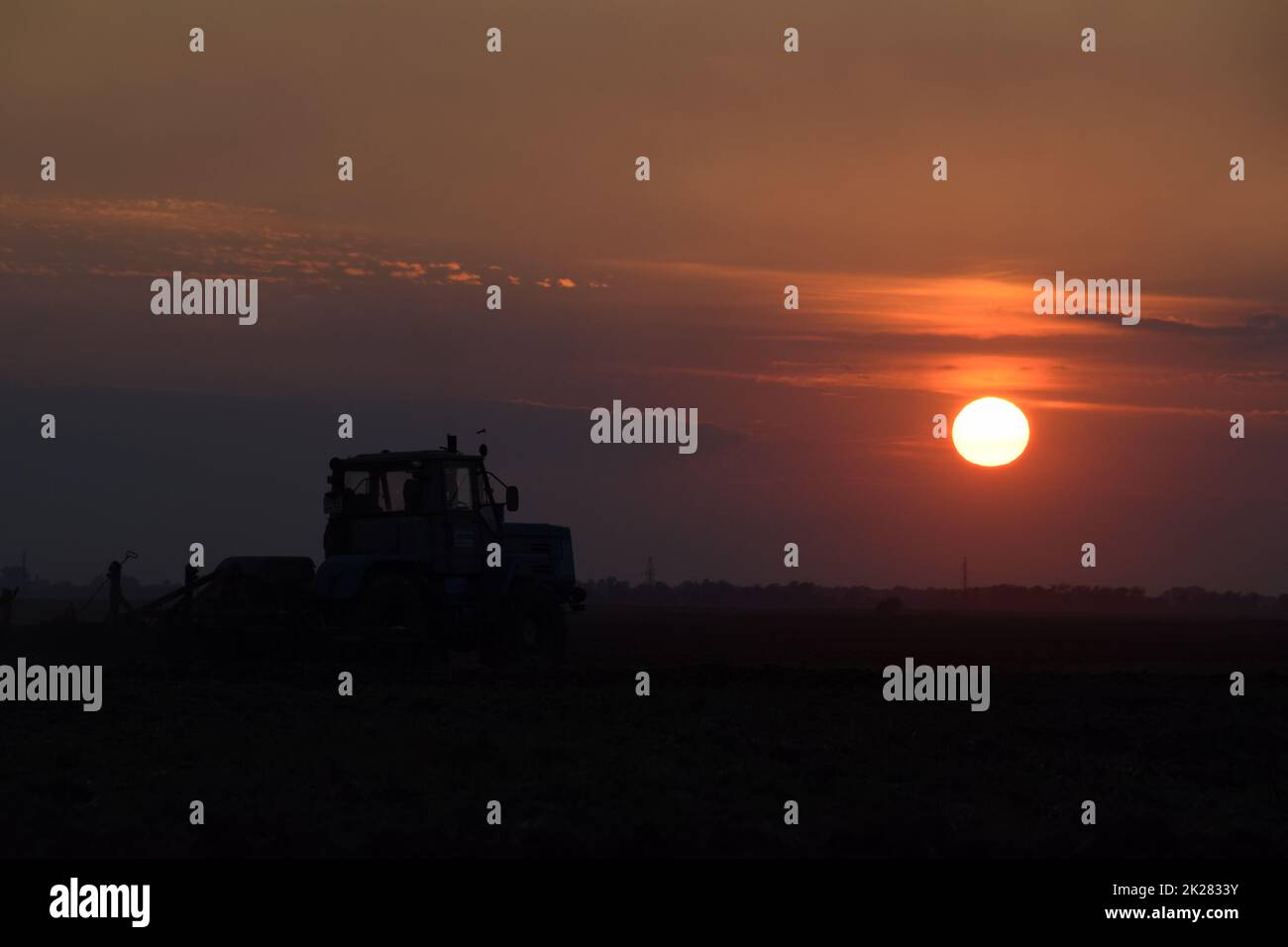 Tractor plowing plow the field on a background sunset. tractor ...
