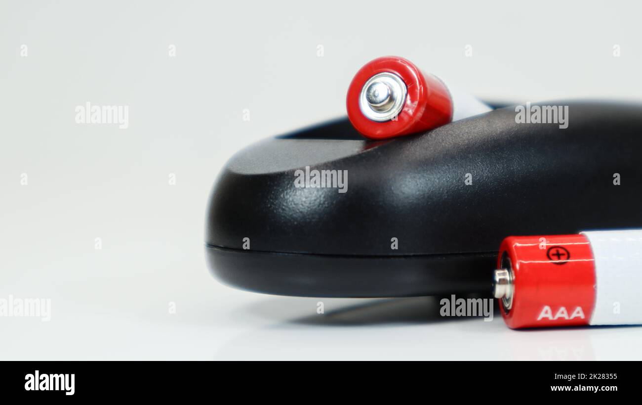 Black TV remote control with AAA alkaline batteries on a white ...