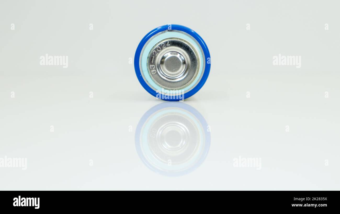 Large battery type D or C cell on white background with reflection. View of a metallic alkaline ...