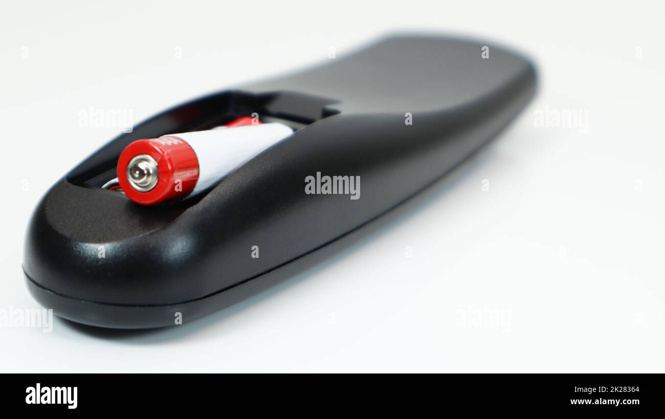 Black TV remote control with AAA alkaline batteries on a white ...