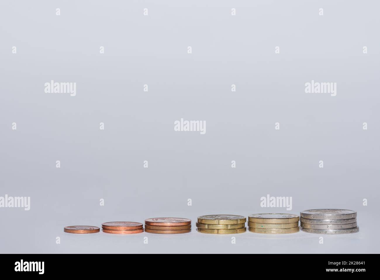 many euro coins stacked in a row increasing in value with gray ...