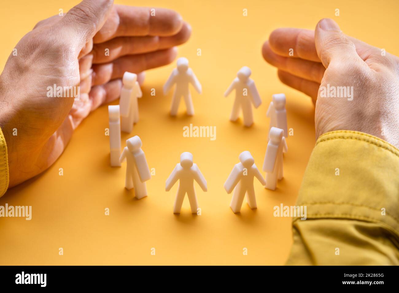Businessperson's Hand Protecting Person Figures Stock Photo - Alamy