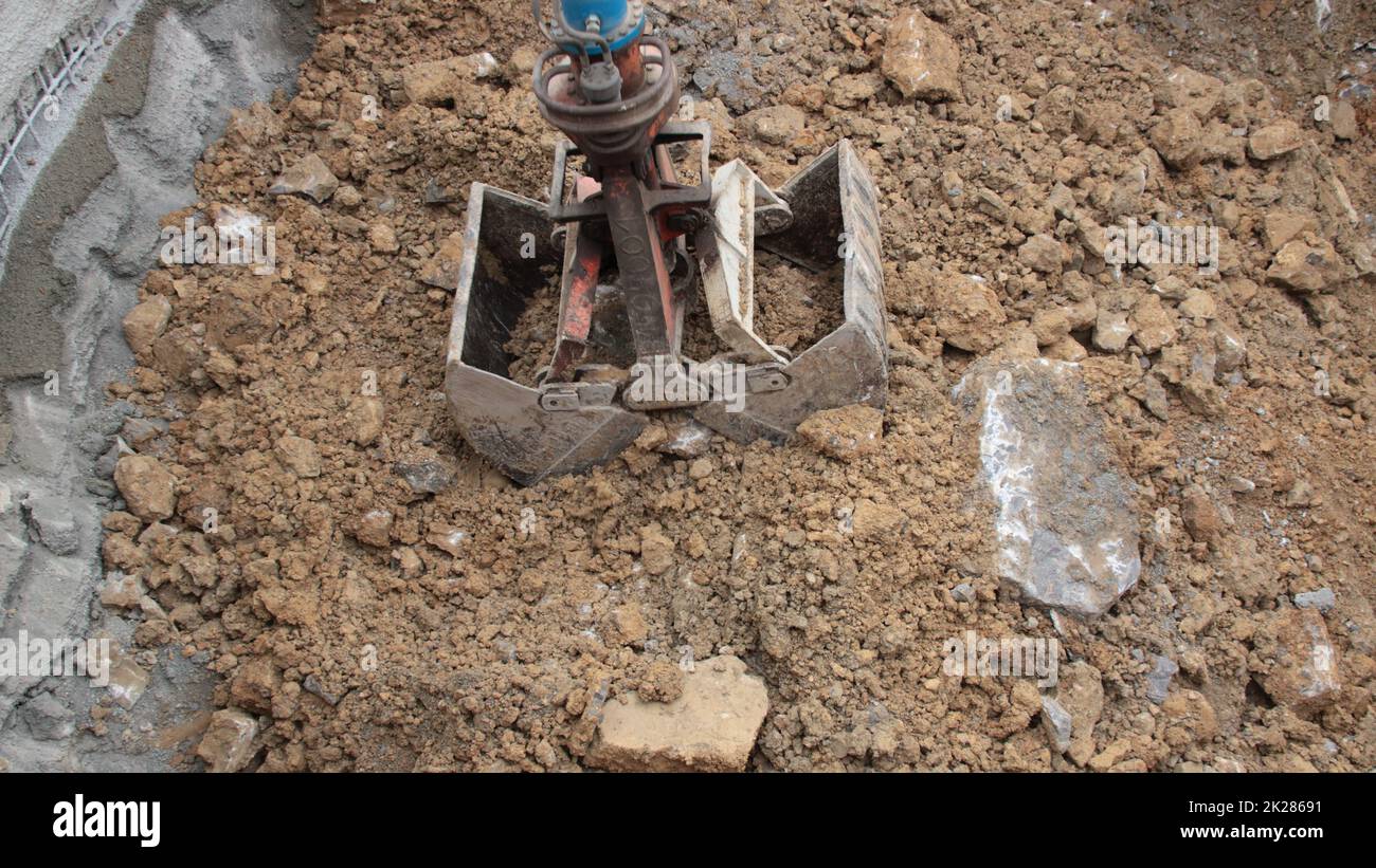 Excavator shovel digs into a graveled ground Stock Photo - Alamy