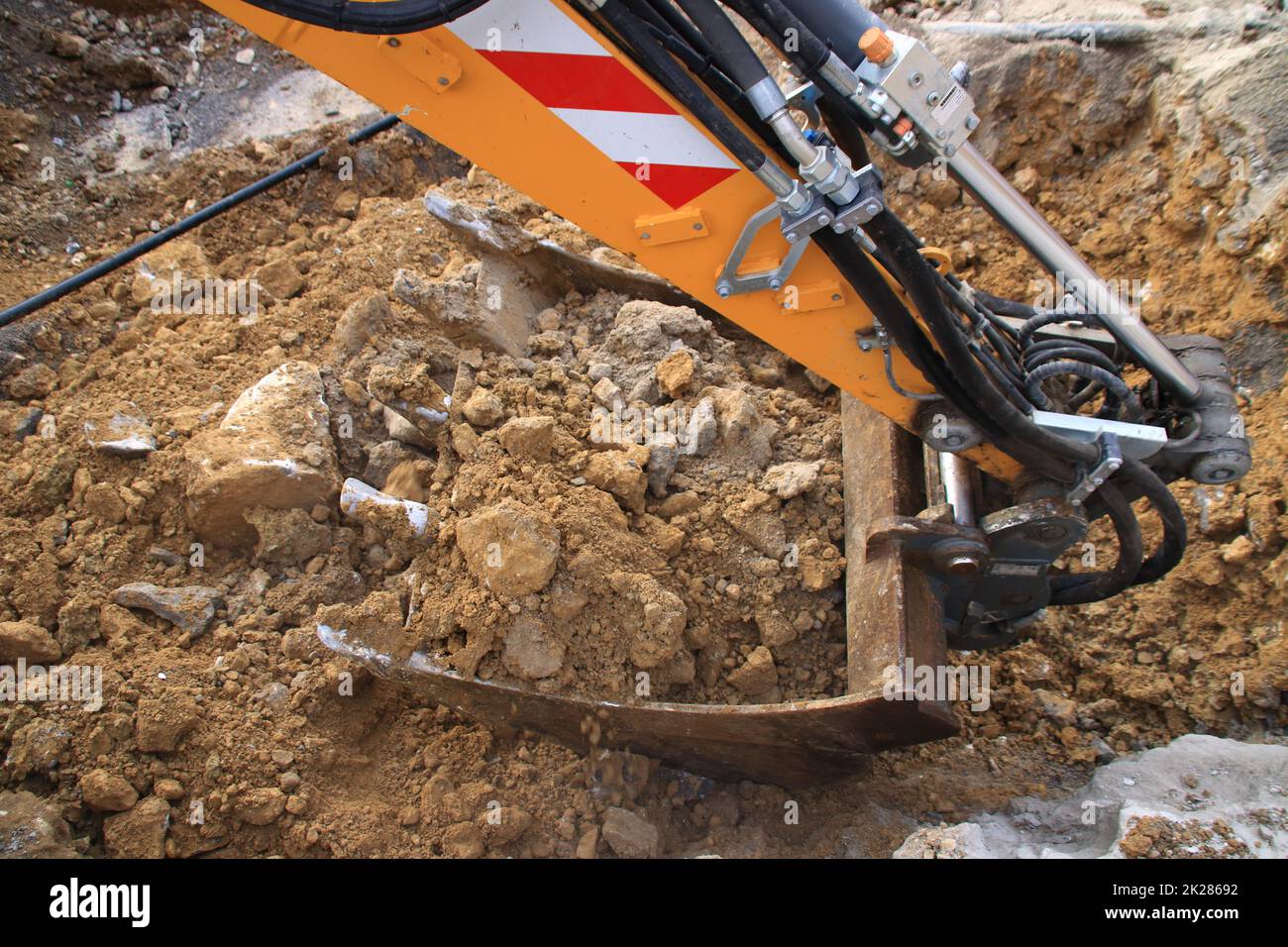 Excavator shovel digs into a graveled ground Stock Photo - Alamy