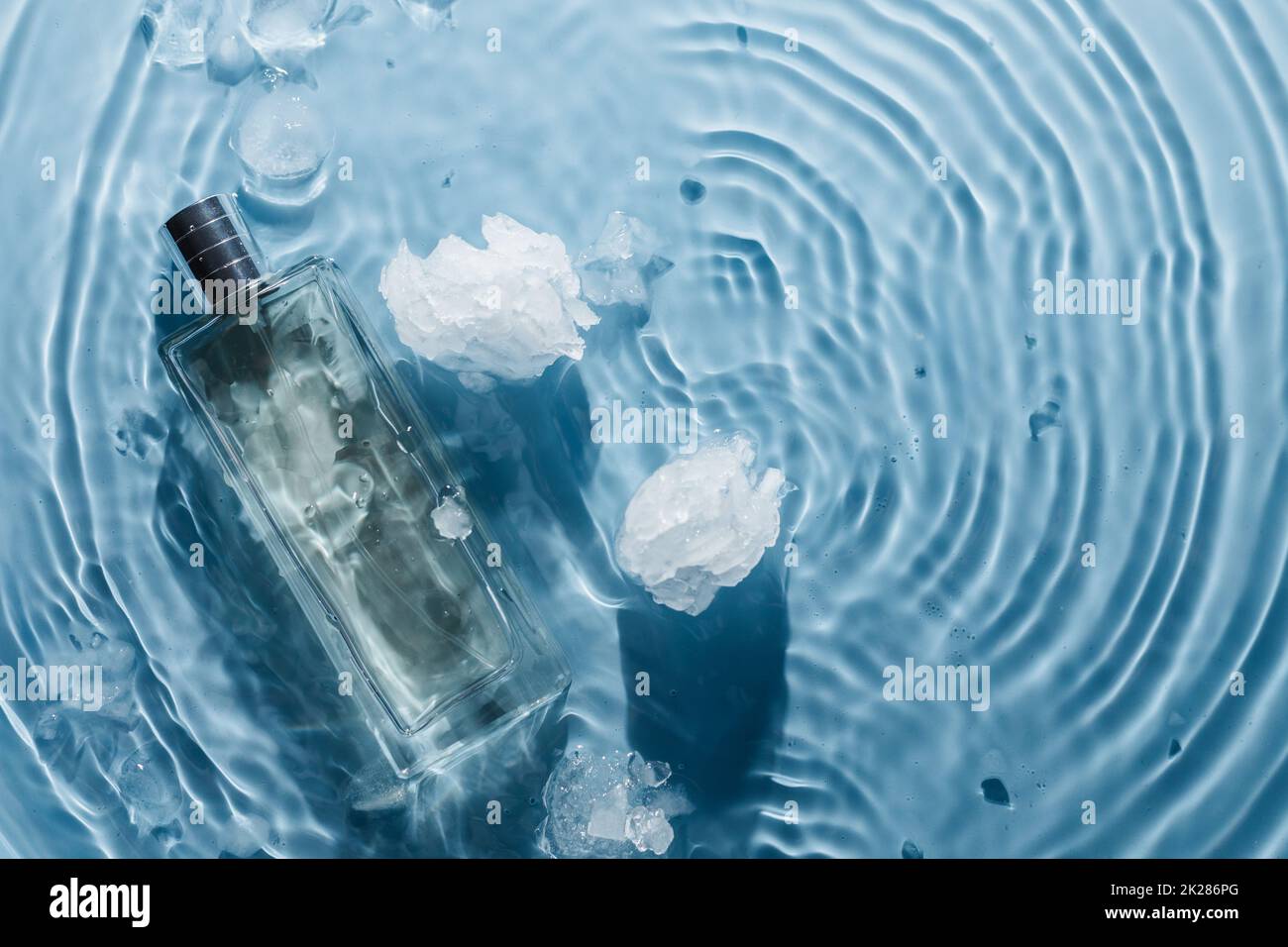 Perfume bottle on blue water wavy background with ice pieces. Fresh ...