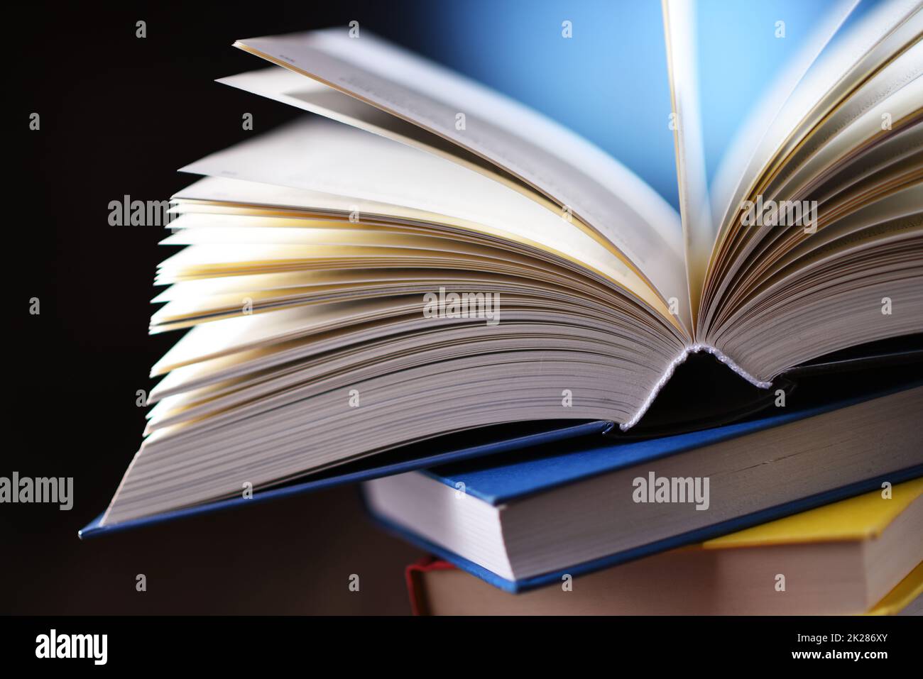 A composition with an open book lying on a stack of other books Stock ...