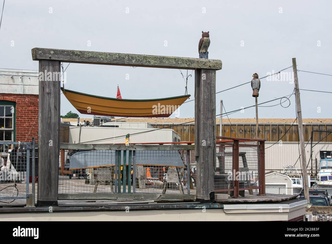 A wooden boat hangs from a gate on the docks in Gloucester Harbor ...