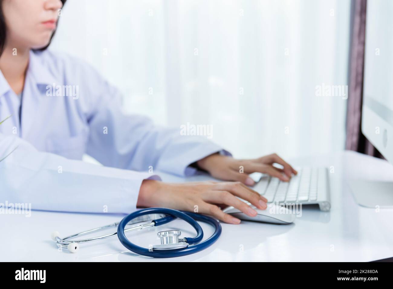 Female doctor with stethoscope typing on keyboard desktop computer ...
