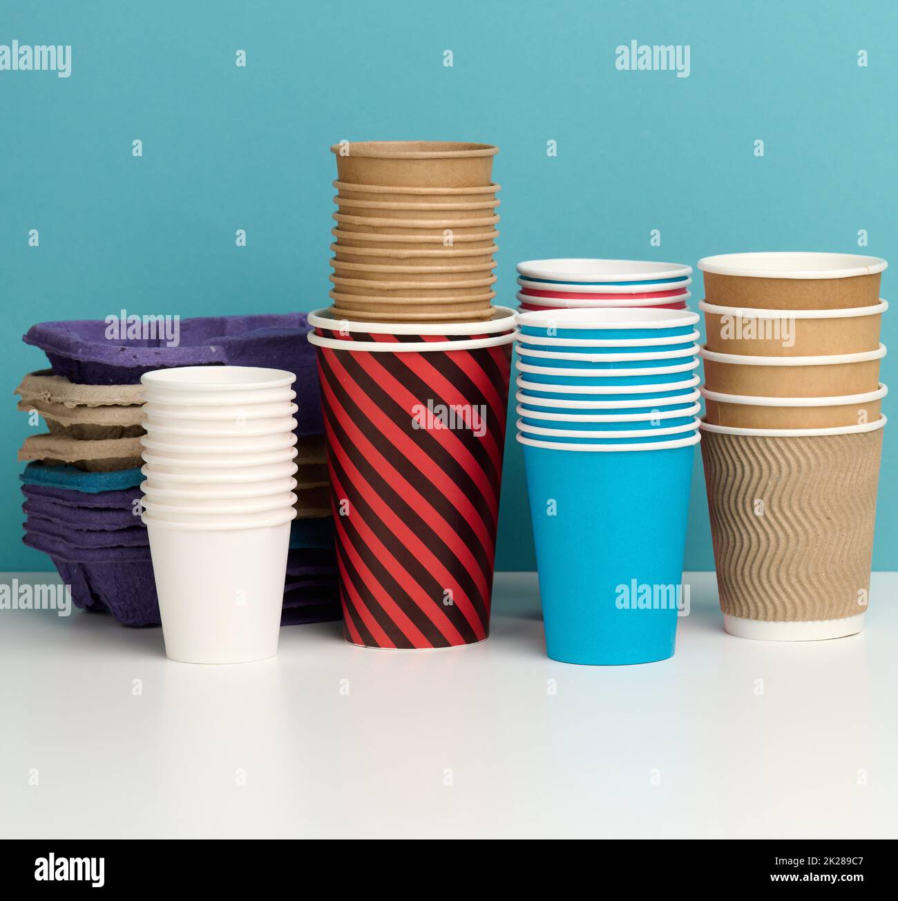 stack of paper disposable multi-colored cups and stand on white table ...