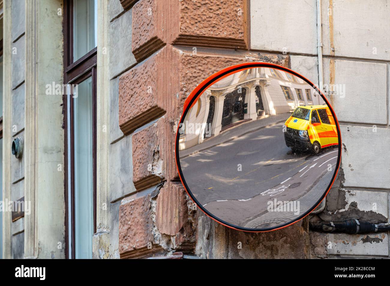 traffic mirror with a yellow ambulance emergency car parked on the side ...