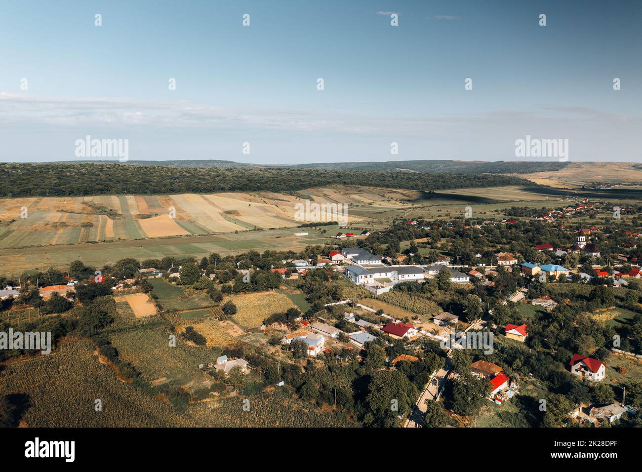 Aerial rural village landscape with yellow patched agriculture fields ...