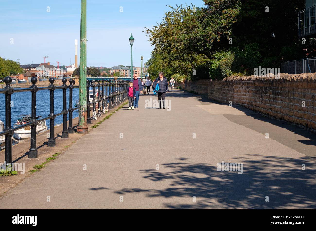 People walking along a city river Stock Photo - Alamy