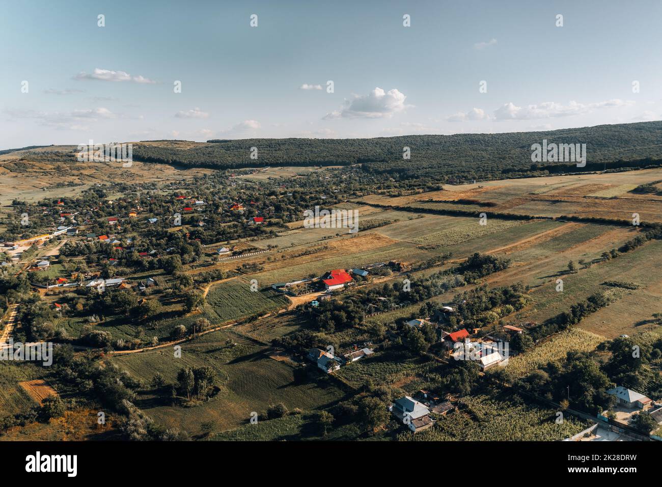 Aerial rural village landscape with yellow patched agriculture fields ...