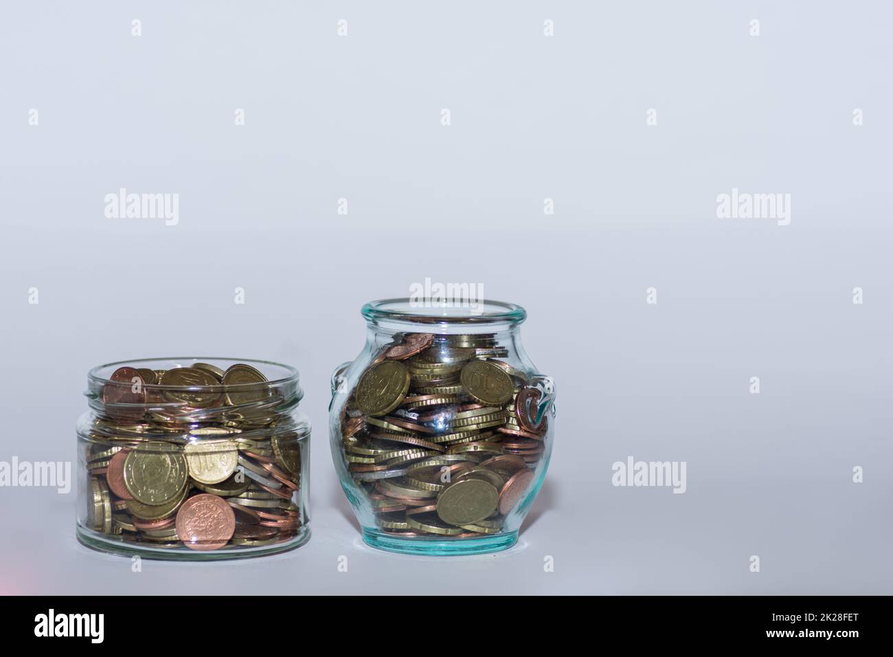 saved money in two jars with many different euro coins for financial ...