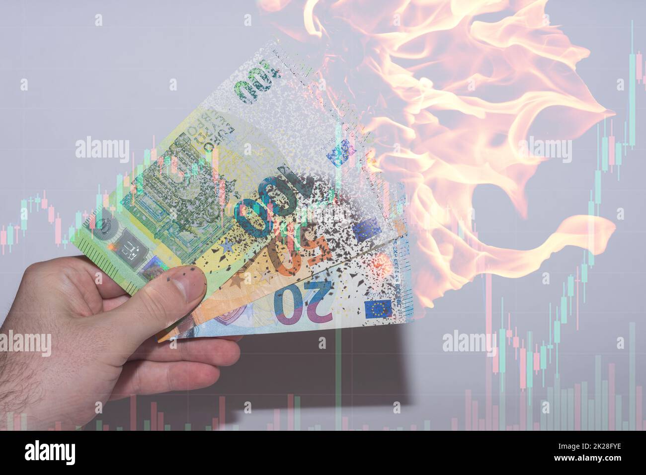 hand helding three burning and disolving euro bank notes with a chart ...