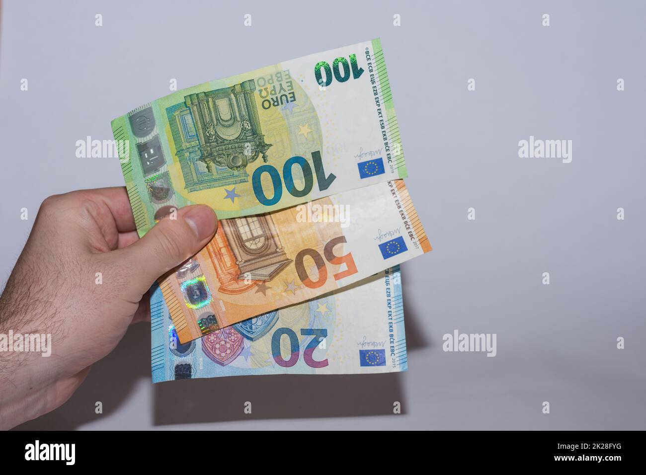 three euro bank notes held in one hand to the side with gray Stock ...