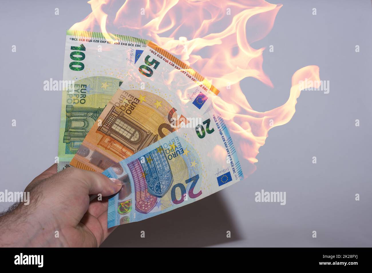hand helding three burning euro bank notes inflation in the finance ...