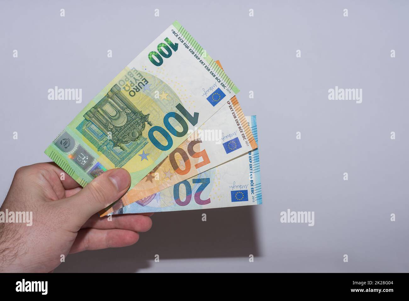 three euro bank notes held in one hand to the top with gray Stock Photo ...