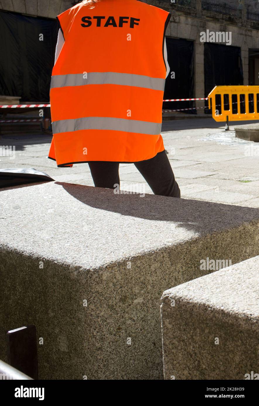 Staff worker watching security area marked by mobile fence and cones ...