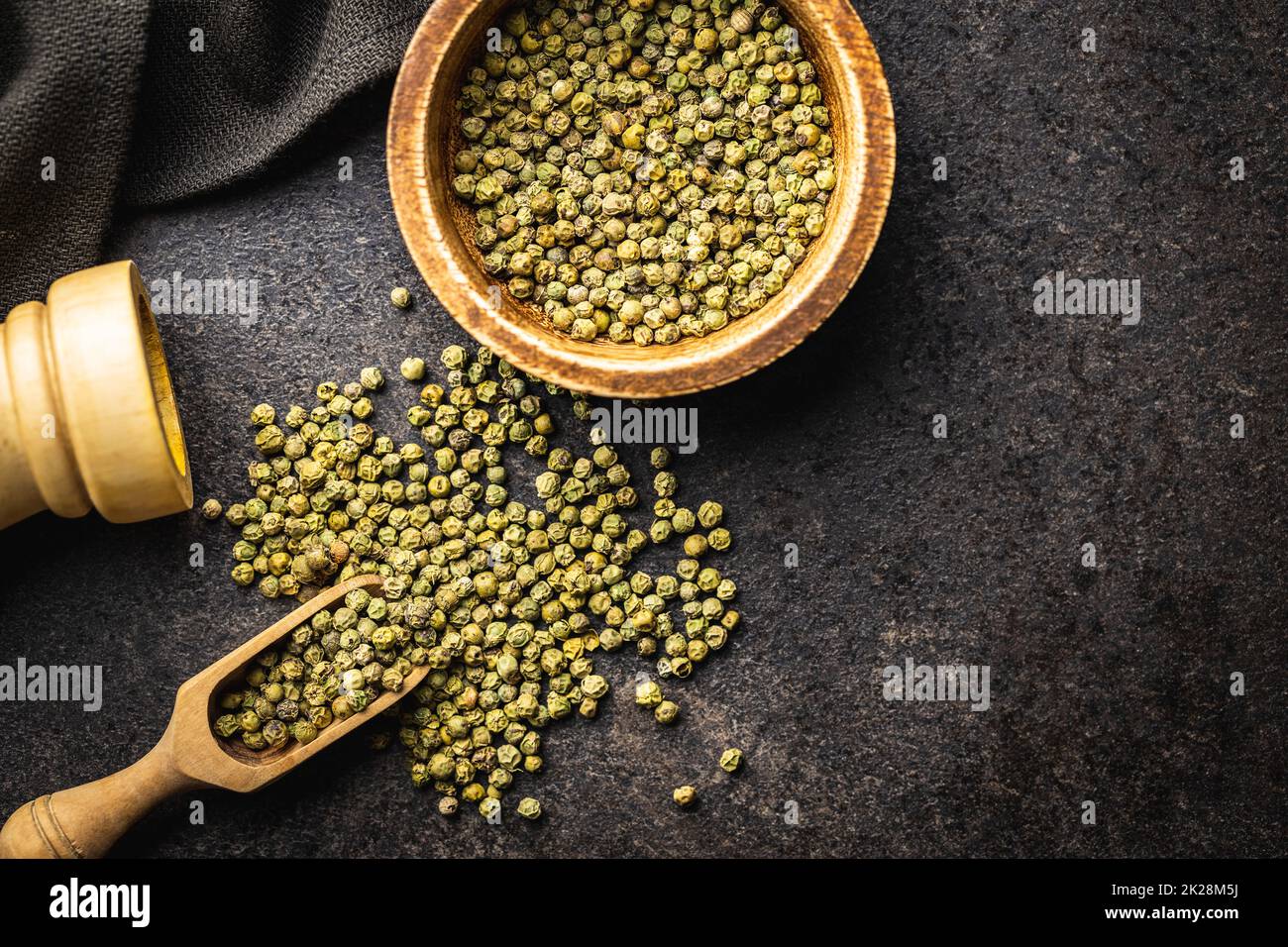 Dried green peppercorn. Dry green pepper spice in scoop on black table ...