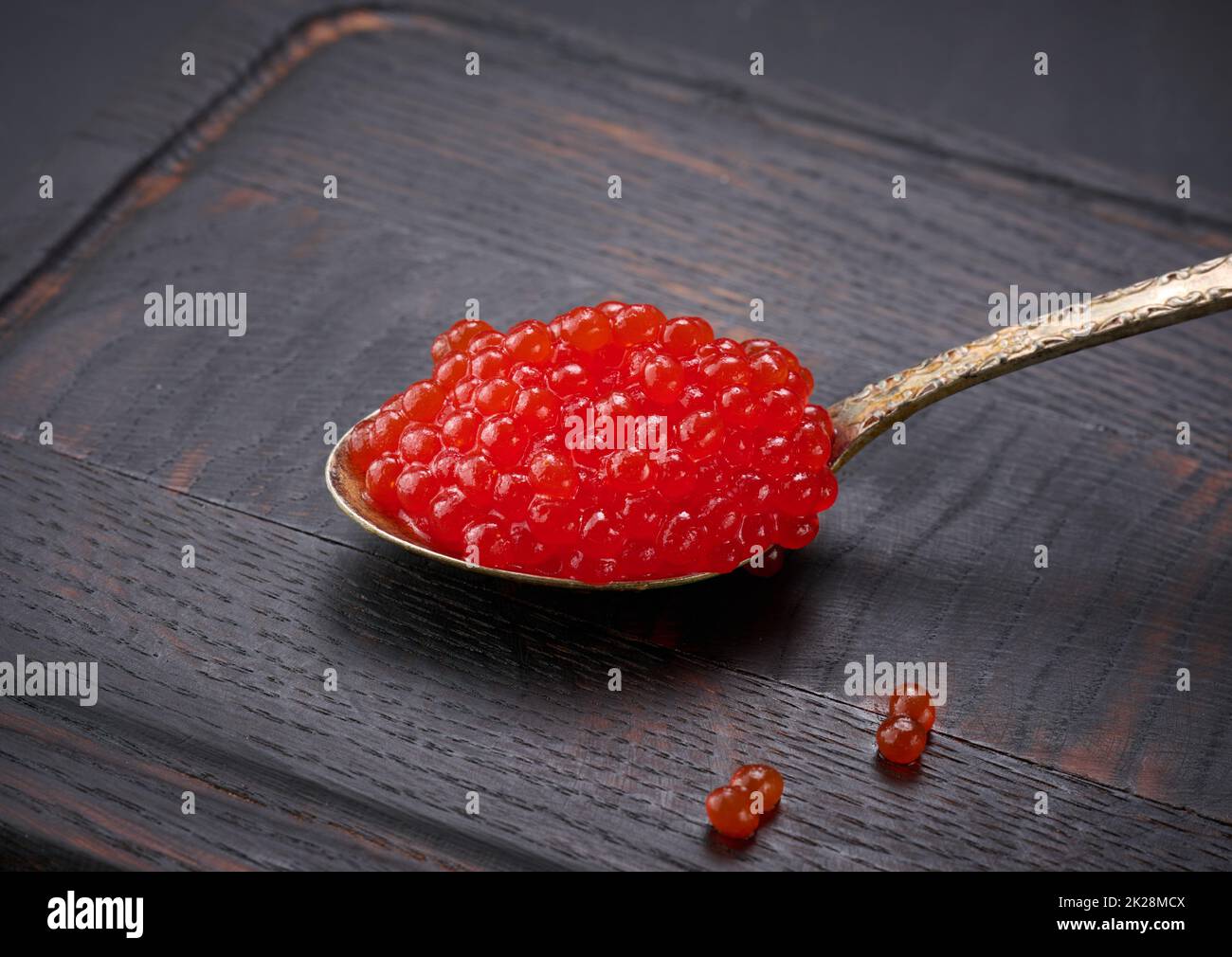 grainy red caviar in a metal spoon on a wooden board Stock Photo - Alamy