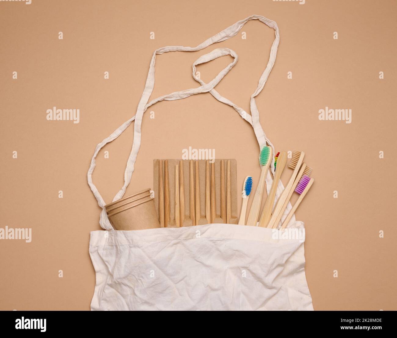 white cotton bag, paper cups and wooden toothbrushes on a brown ...